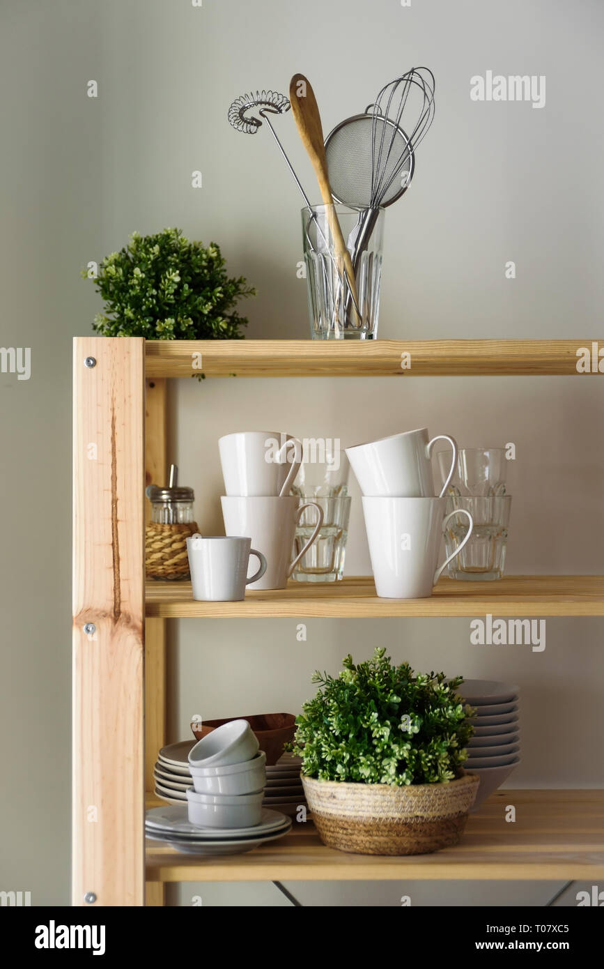 Dish and decorations on open wooden shelves in white kitchen Stock ...