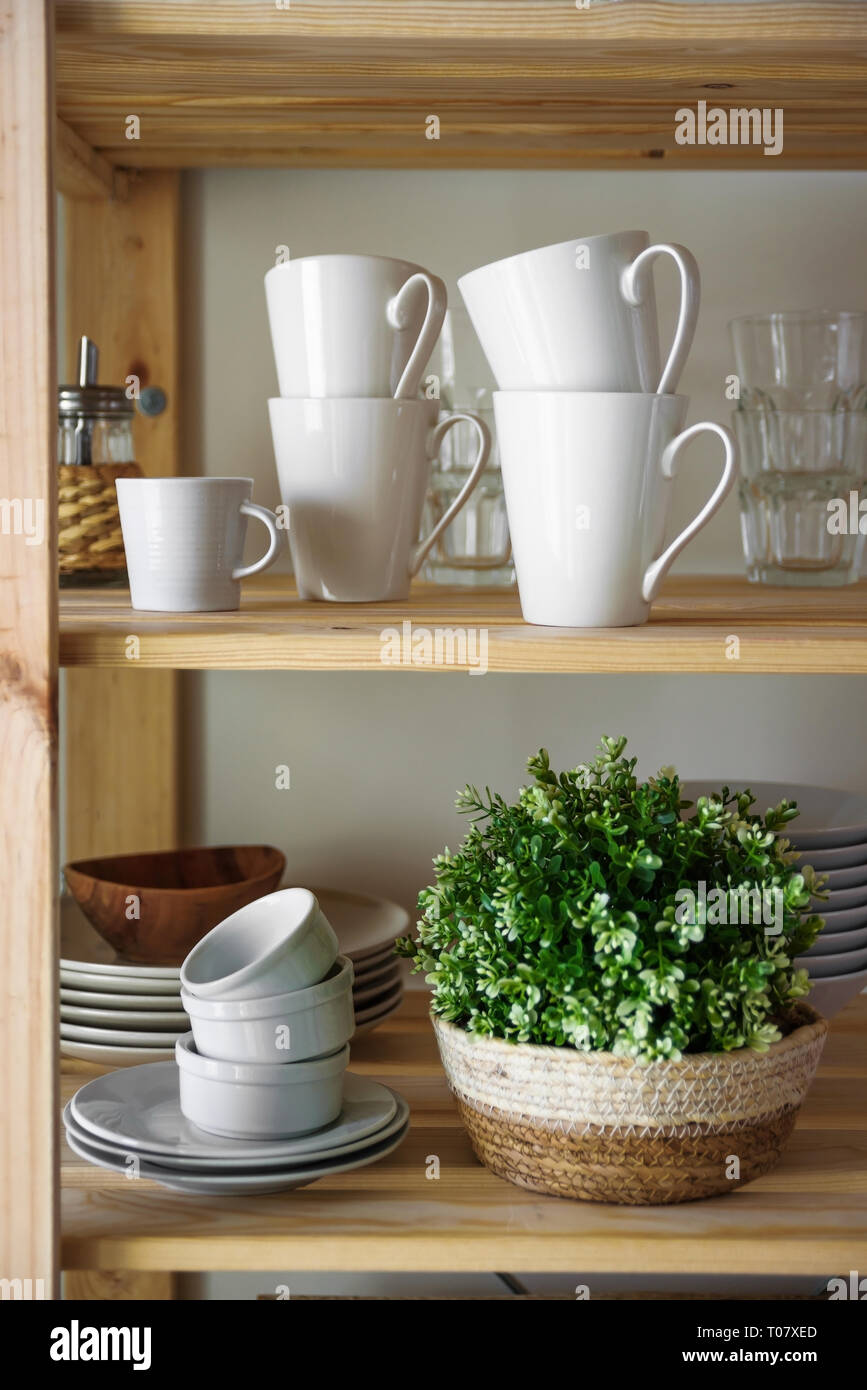 Dish and decorations on open wooden shelves in white kitchen Stock ...