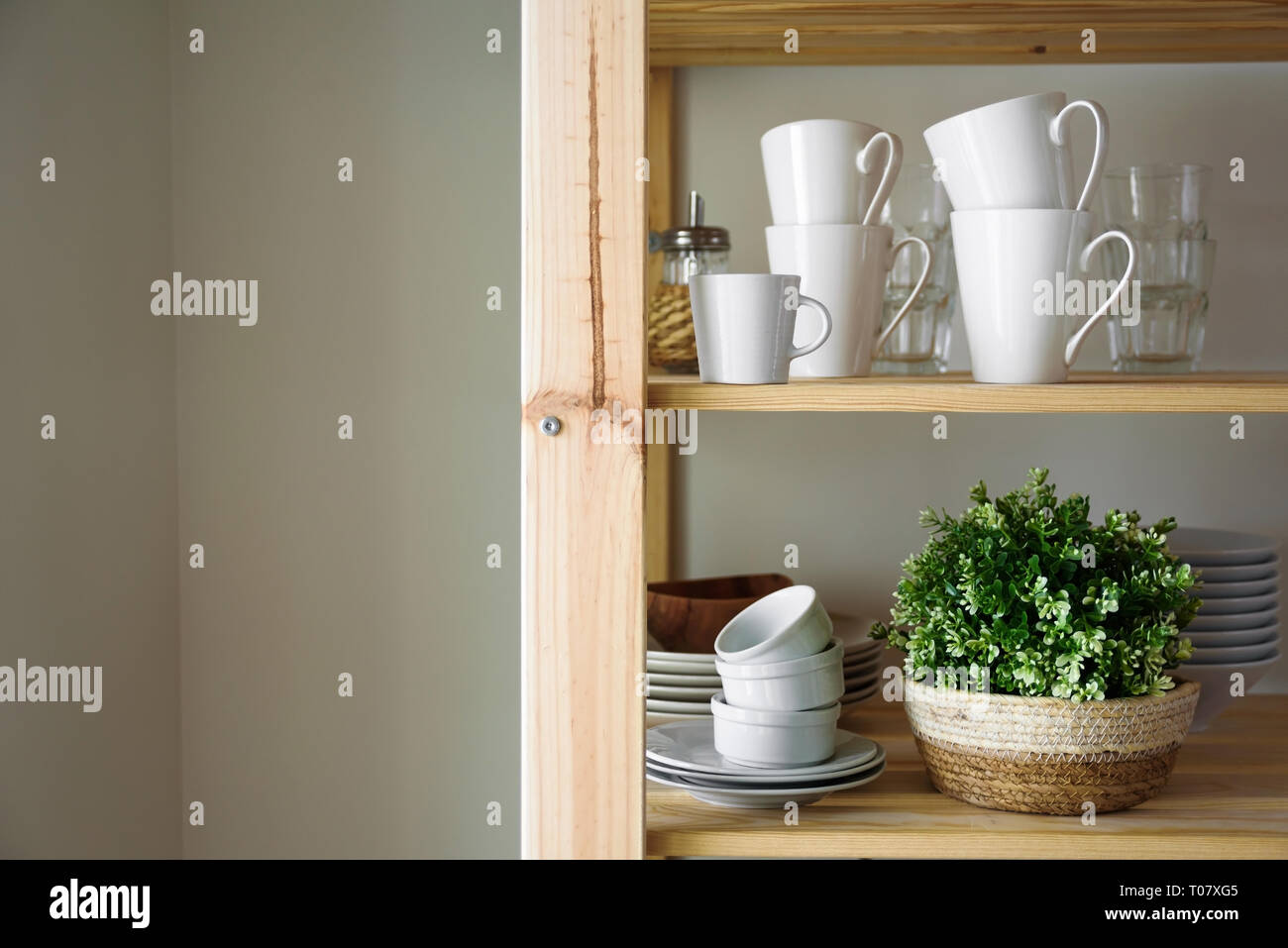 Dish and decorations on open wooden shelves in white kitchen Stock ...