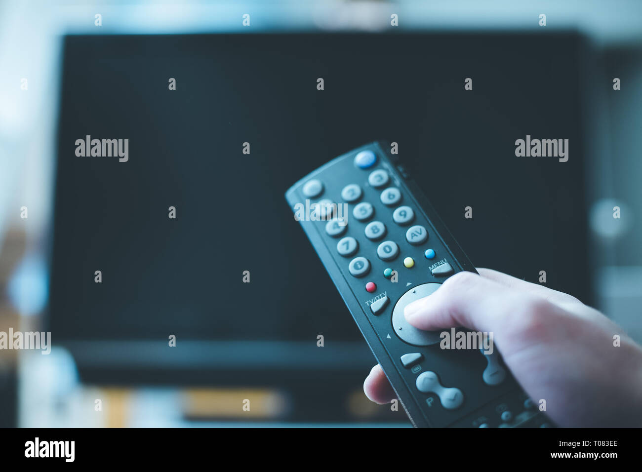 TV remote control in the foreground, tv in the blurry background. Film ...