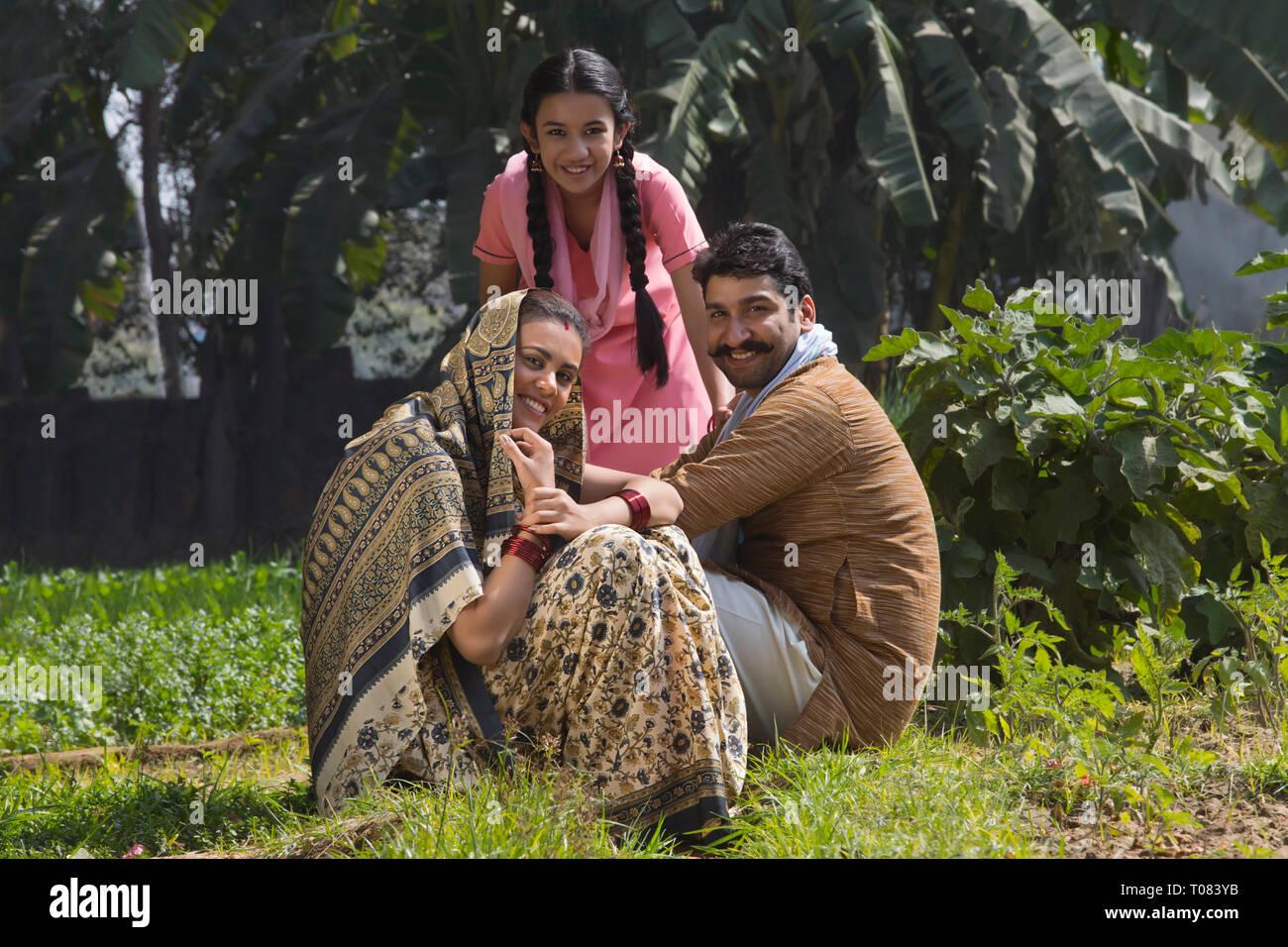 Happy and smiling rural family sitting in their agriculture field Stock ...