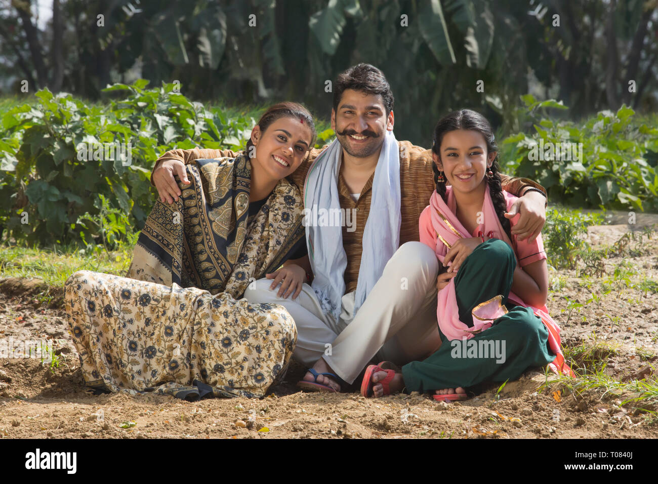 Happy and smiling rural family sitting in their agriculture field Stock ...