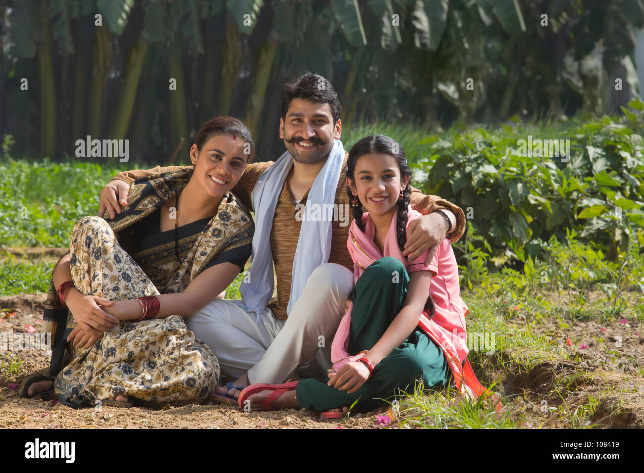 Happy and smiling rural family sitting in their agriculture field Stock ...