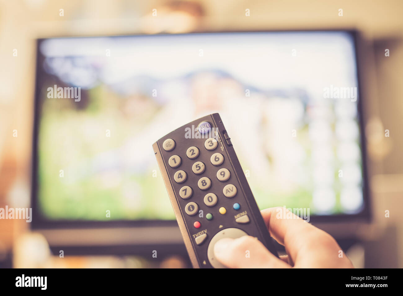 TV remote control in the foreground, tv in the blurry background. Film ...