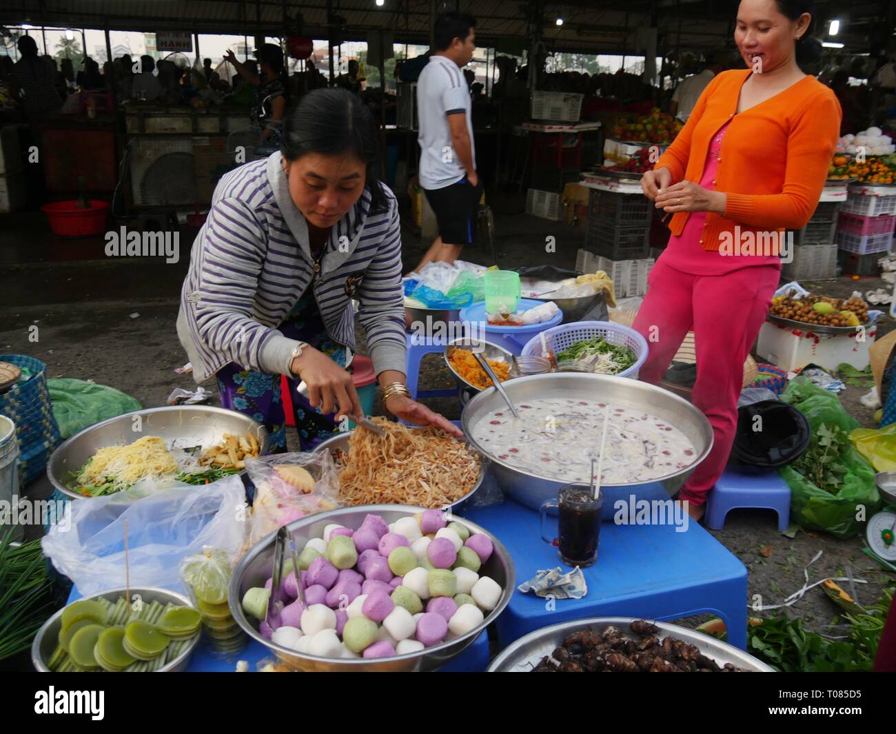CAN THO, VIETNAM--MARCH 2018: A female street vendor scoops a serving ...