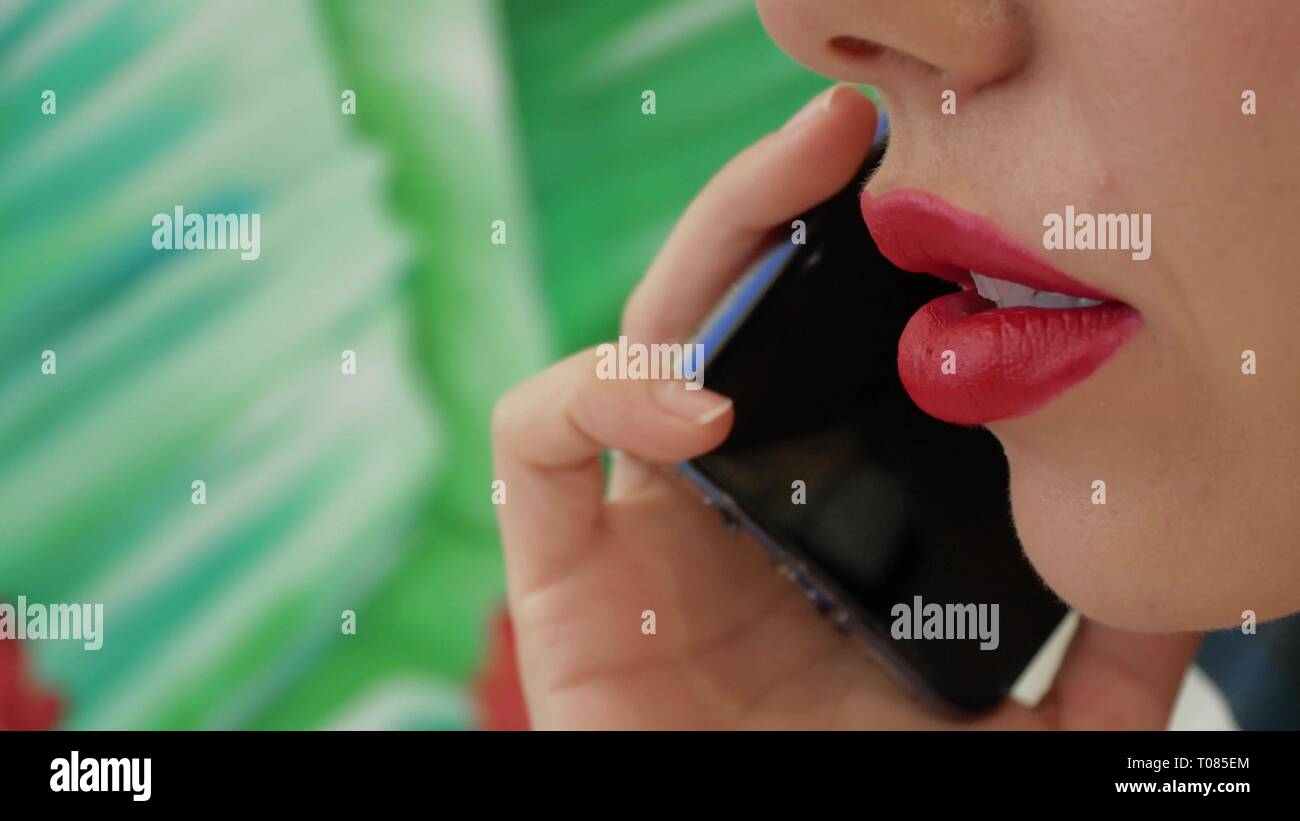 Young woman with beautiful lips talking on the phone on the blurred ...