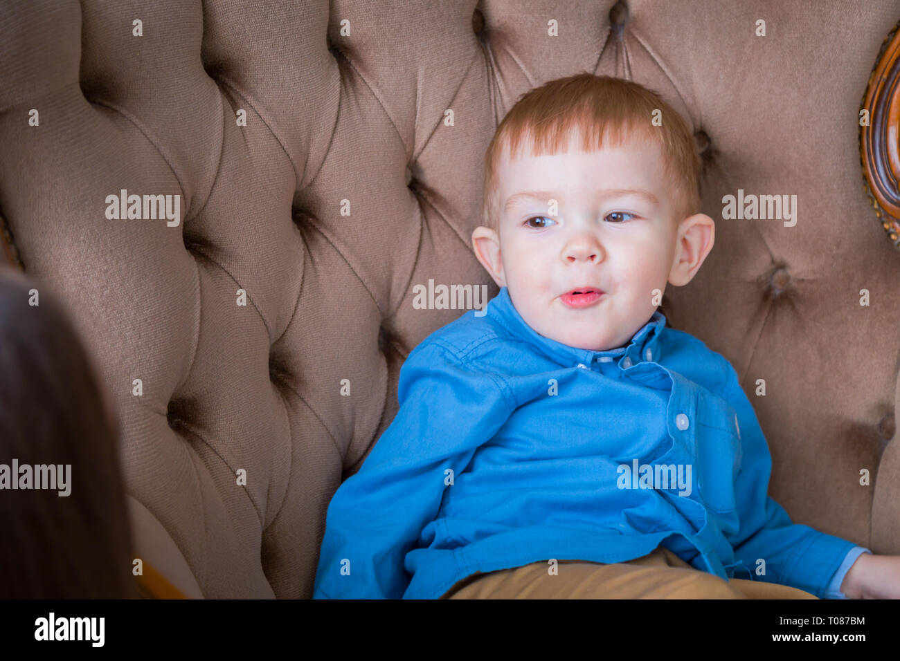 Little happy boy sitting on the chair at home Stock Photo - Alamy