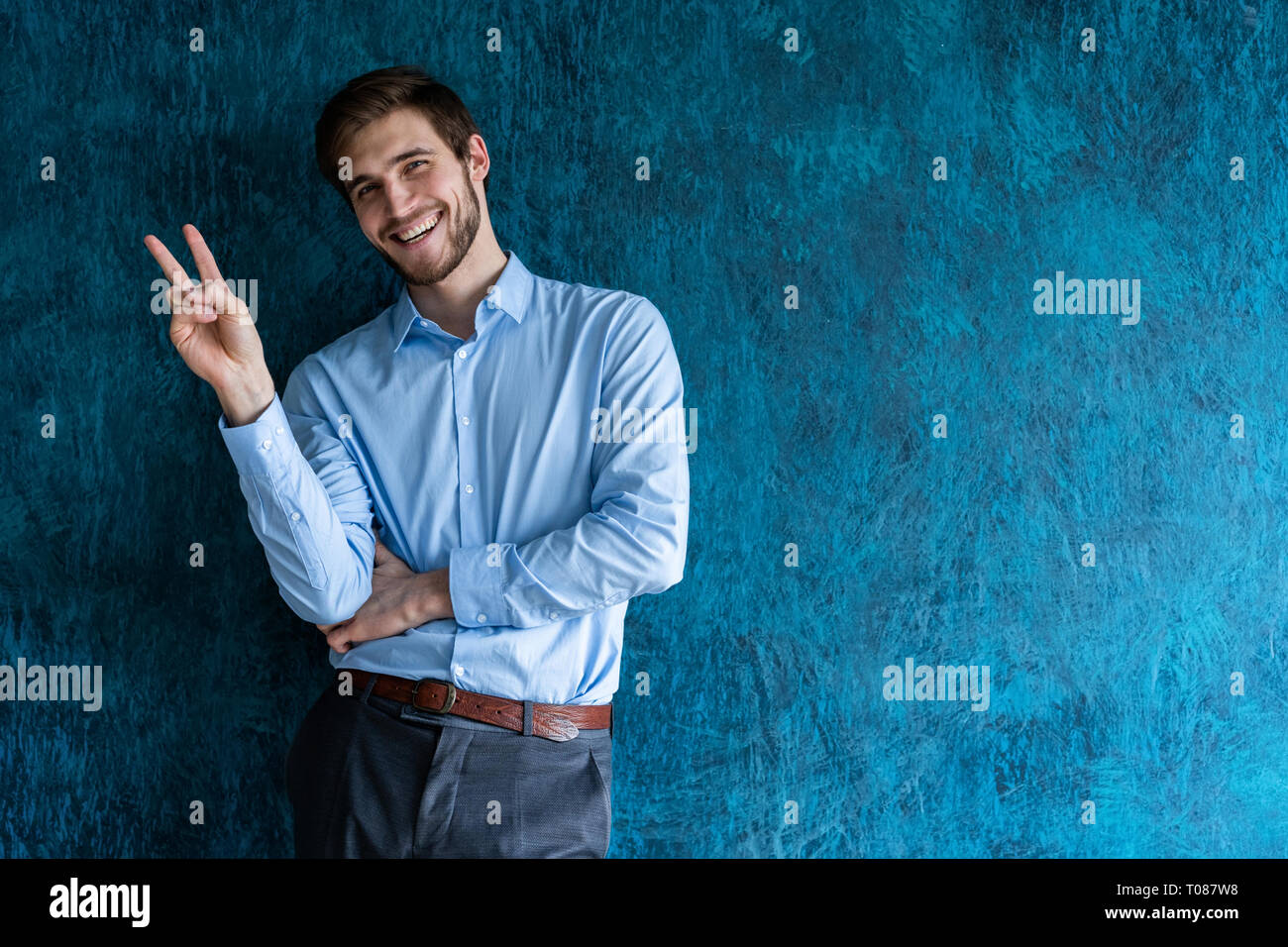 business man in a suit giving the victory sign on blue background Stock ...