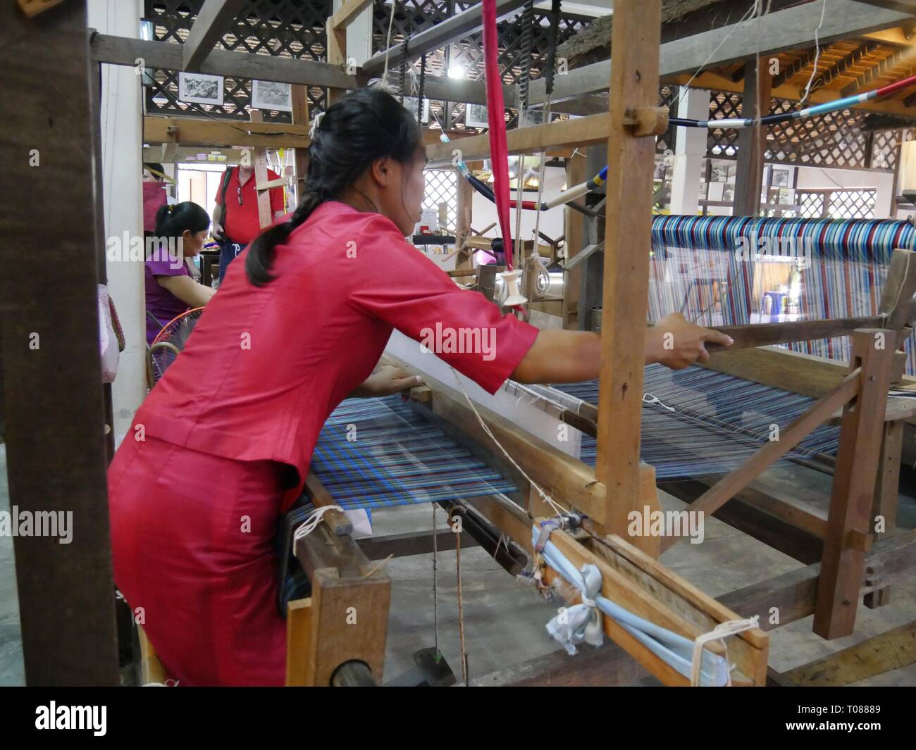 CHIANG MAI, THAILAND—MARCH 2018: A woman weaves colorful silk using a ...