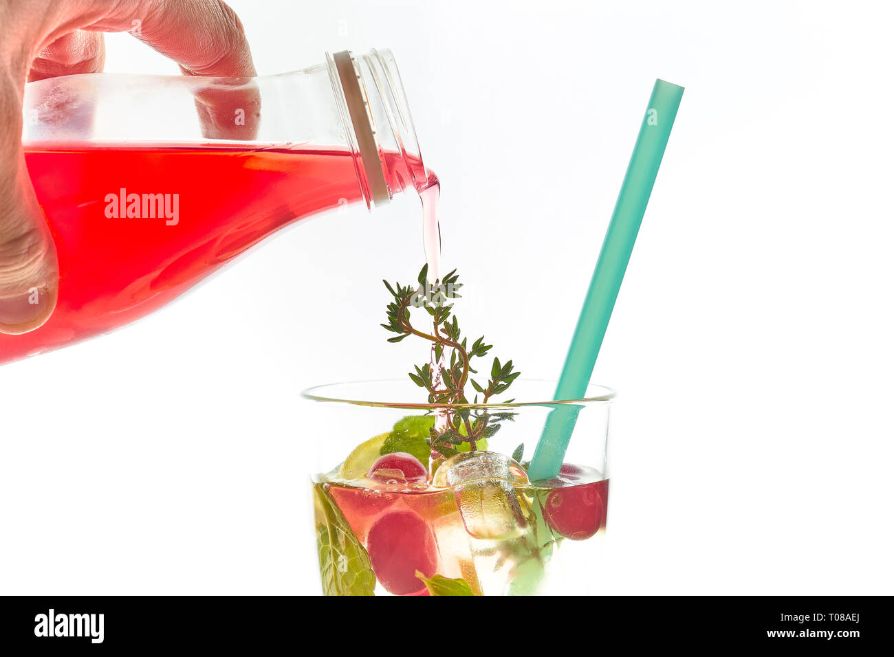 man pours cold berry cocktail in glass with ice, isolated on white ...