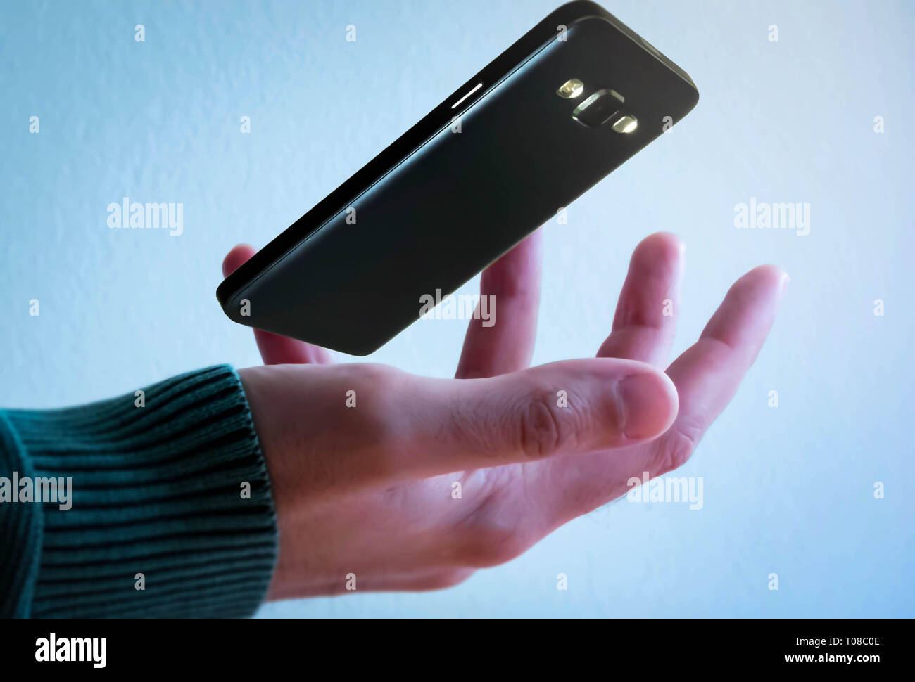 Mobile phone floating above hand Stock Photo - Alamy