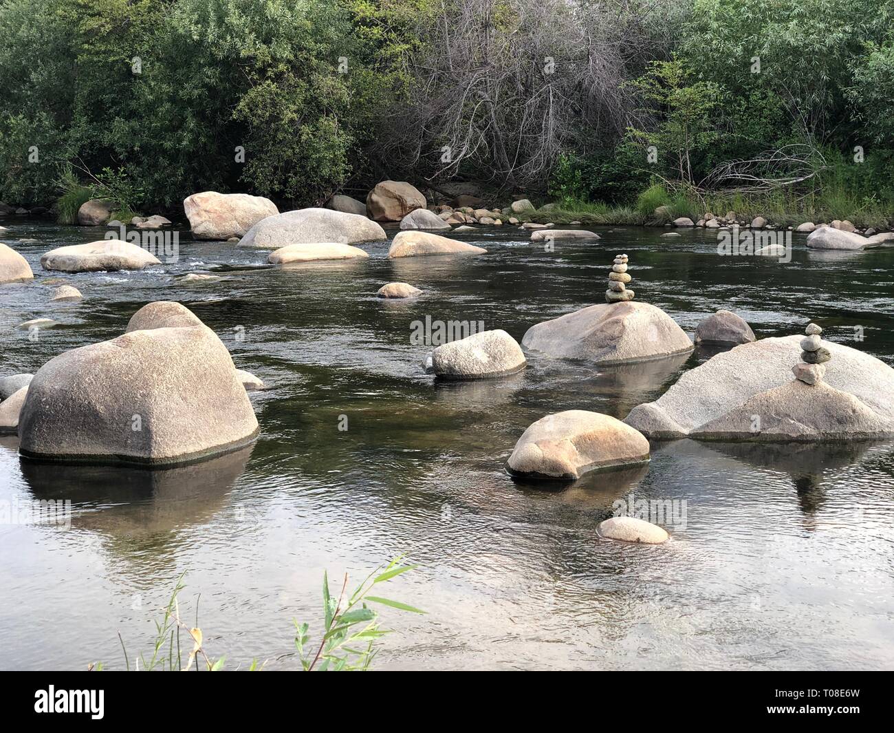 Close up of rocks in the river, with little stones piled on top of each ...