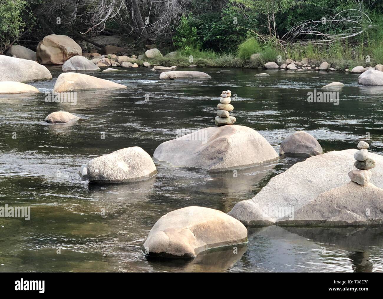 Medium close up of rocks in the river with small stones piled on top of ...