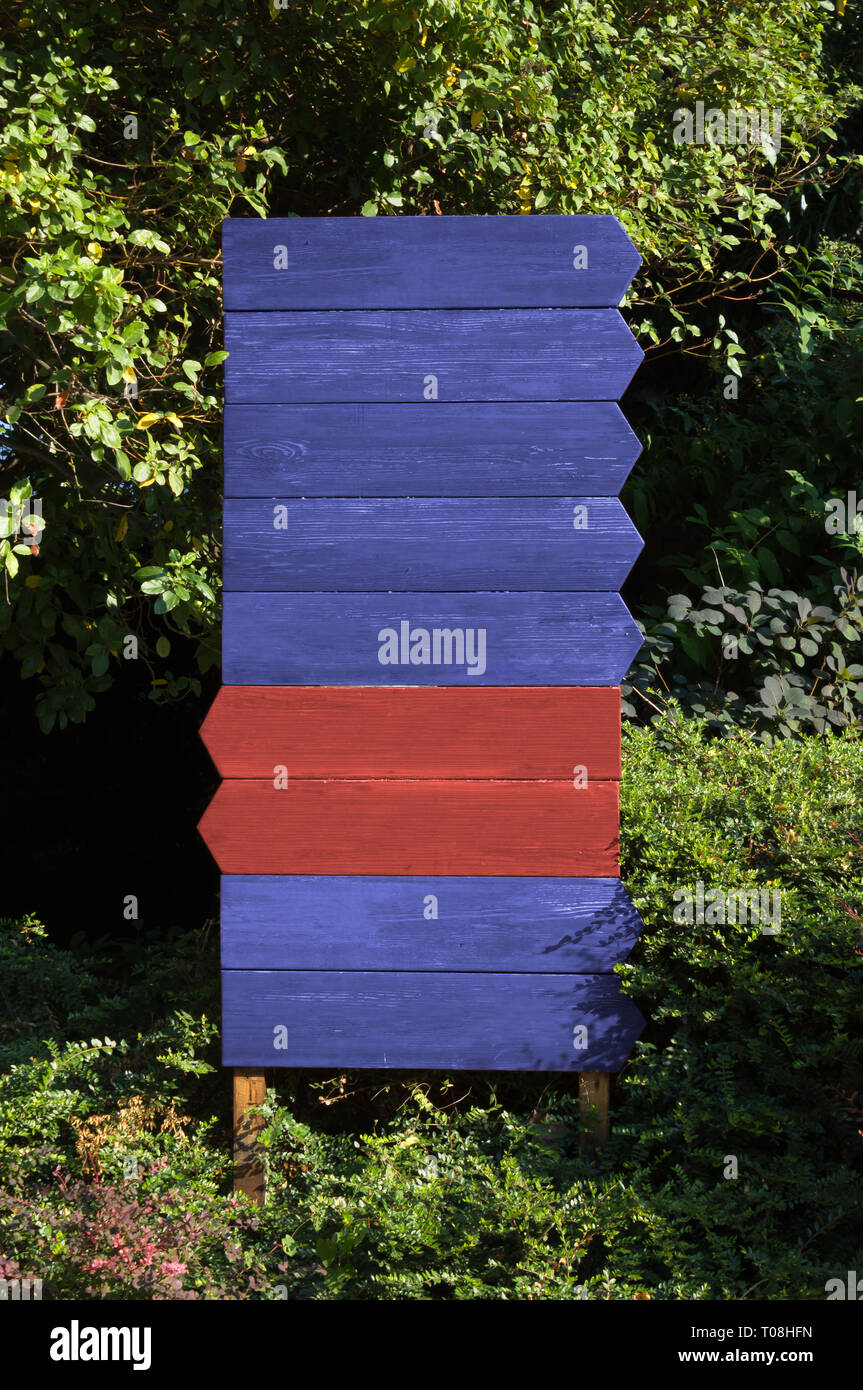 Block of nine wooden empty direction signs, seven blue ones pointing to ...