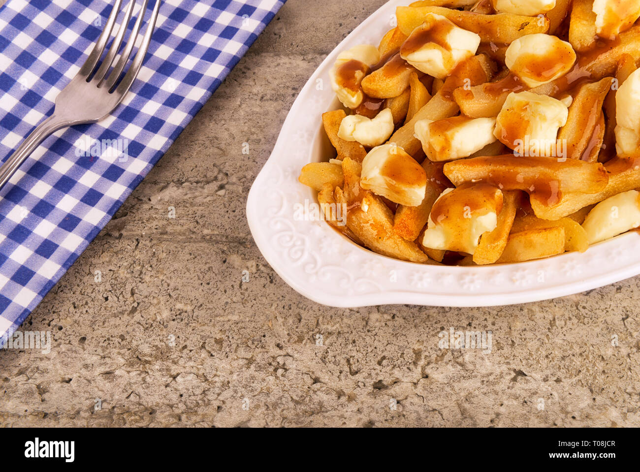 Poutine plate on a concrete background. Cooked with french fries, beef ...