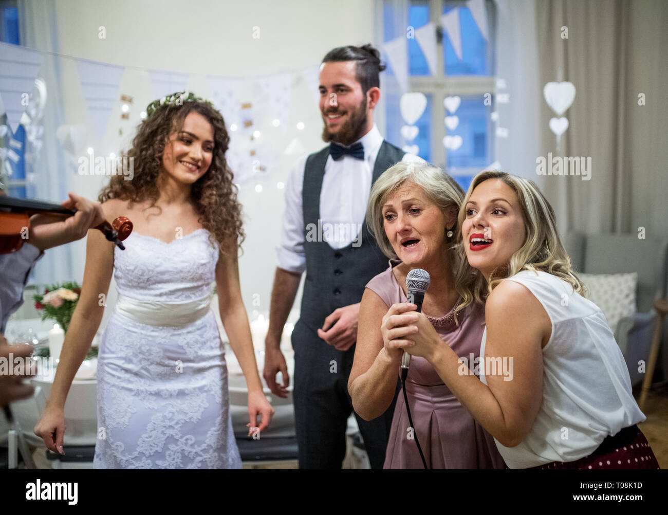 A young bride and groom with other guests dancing and singing on a ...