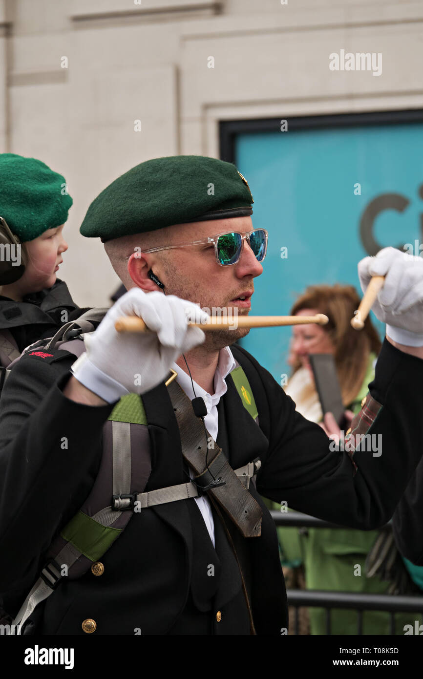 A small child is carried in a rucksack on the back of drummer playing ...