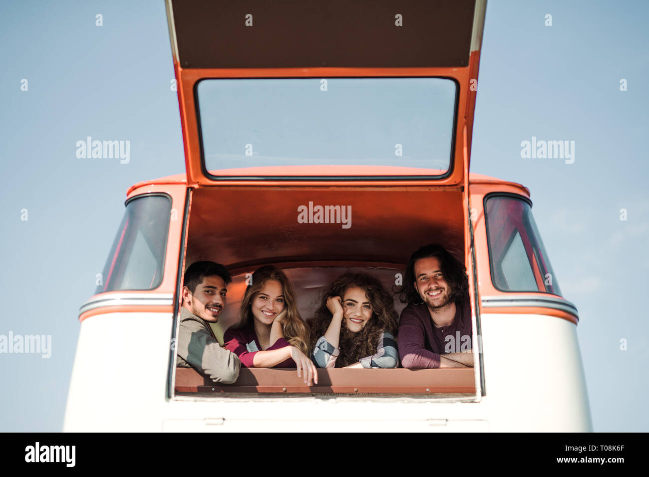 A group of young friends on a roadtrip through countryside, looking out ...