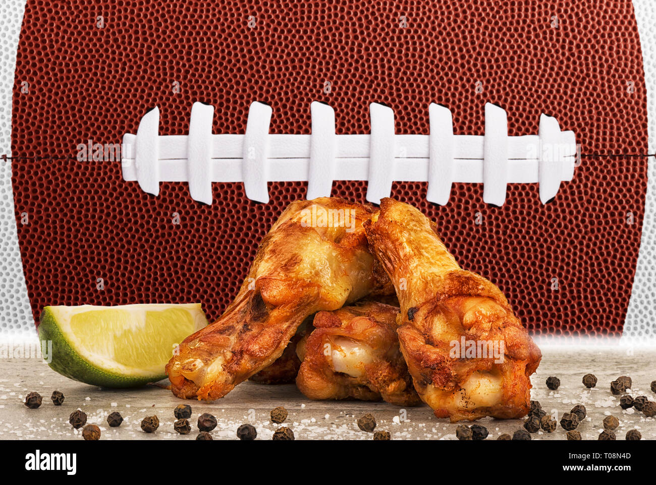 Chicken wings with a lime wedge, salt and peppercorn on concrete table ...