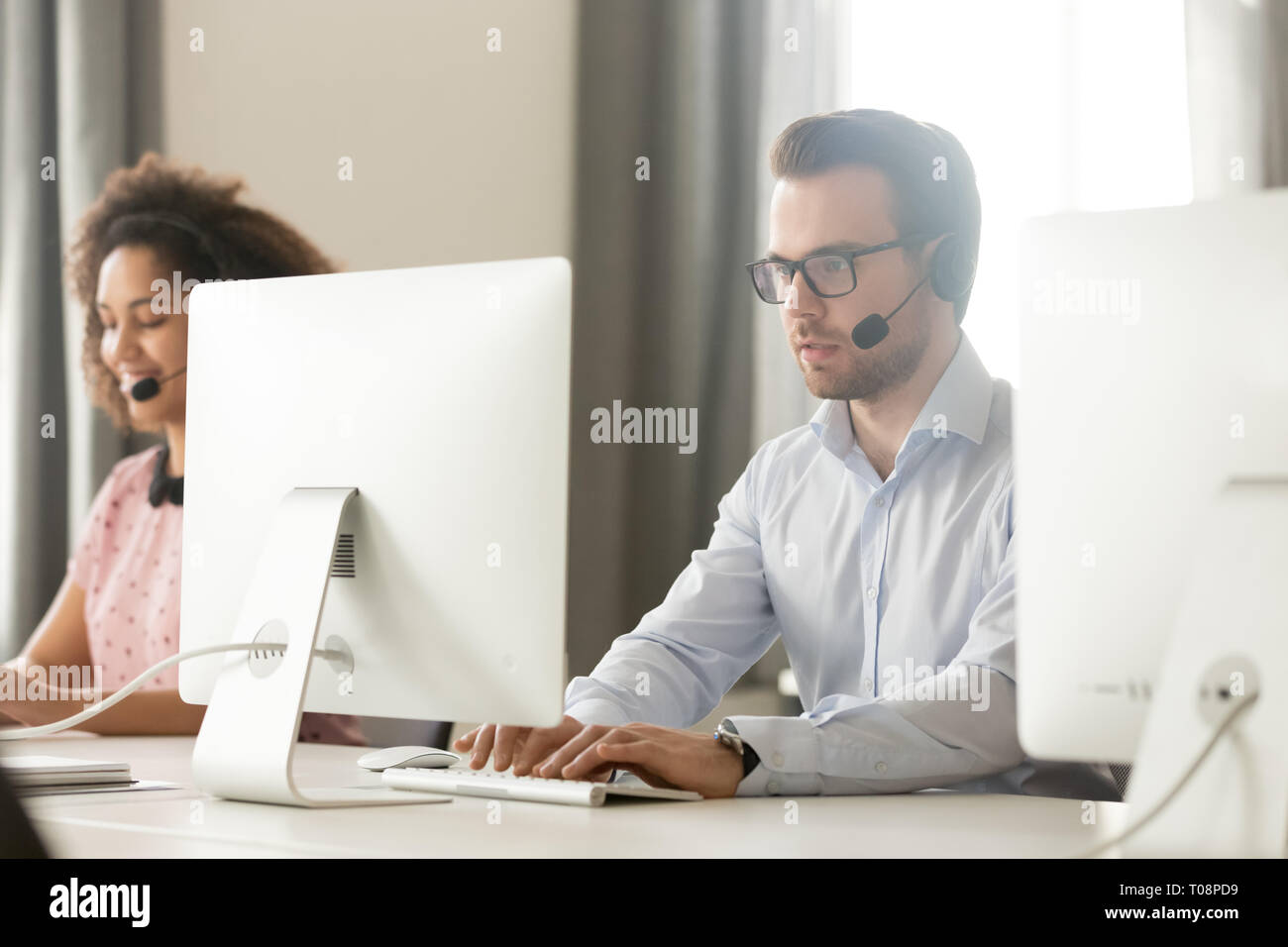 Call center agent in headset using computer in open space Stock Photo ...