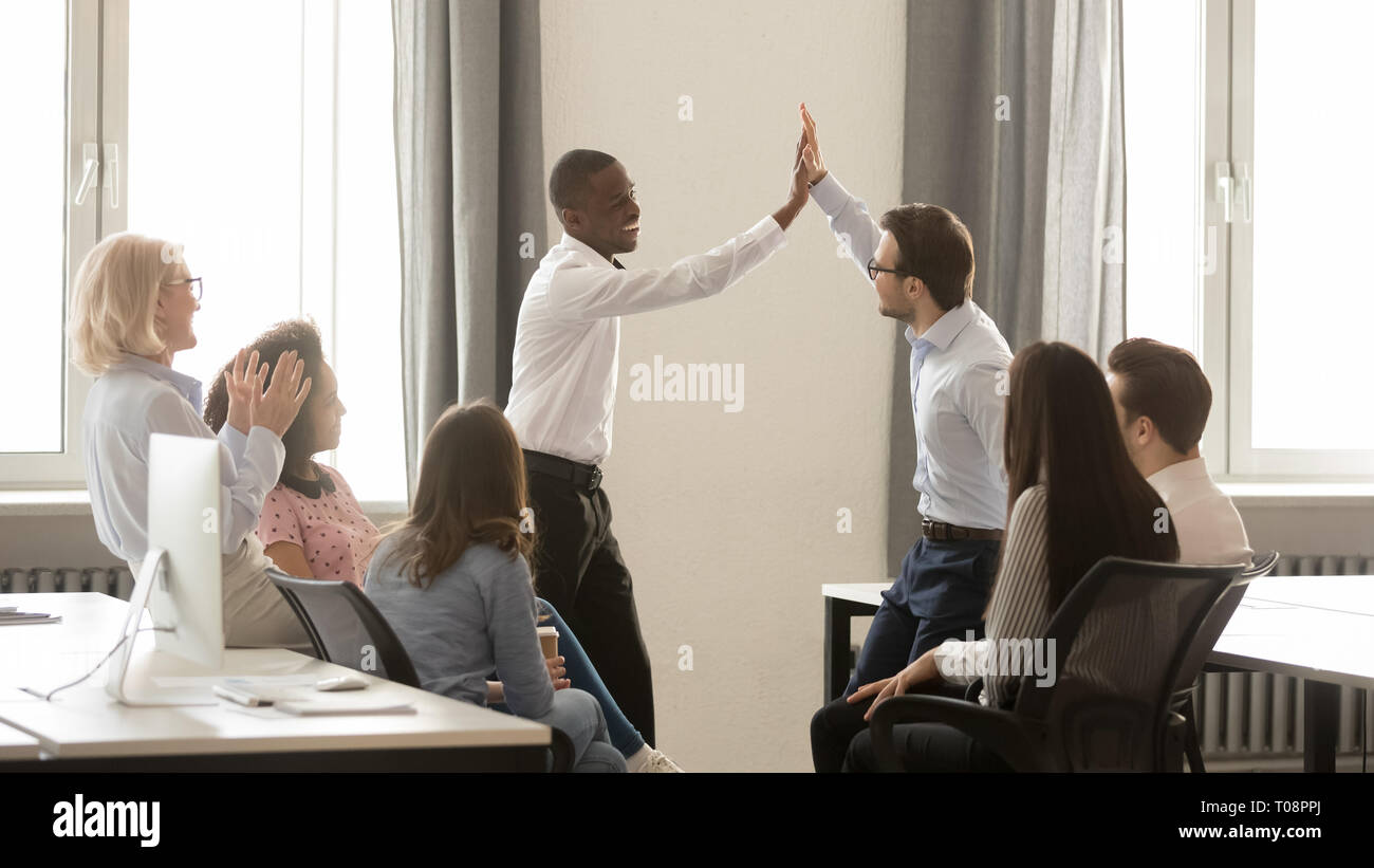 Happy diverse employees giving high five together celebrating shared ...