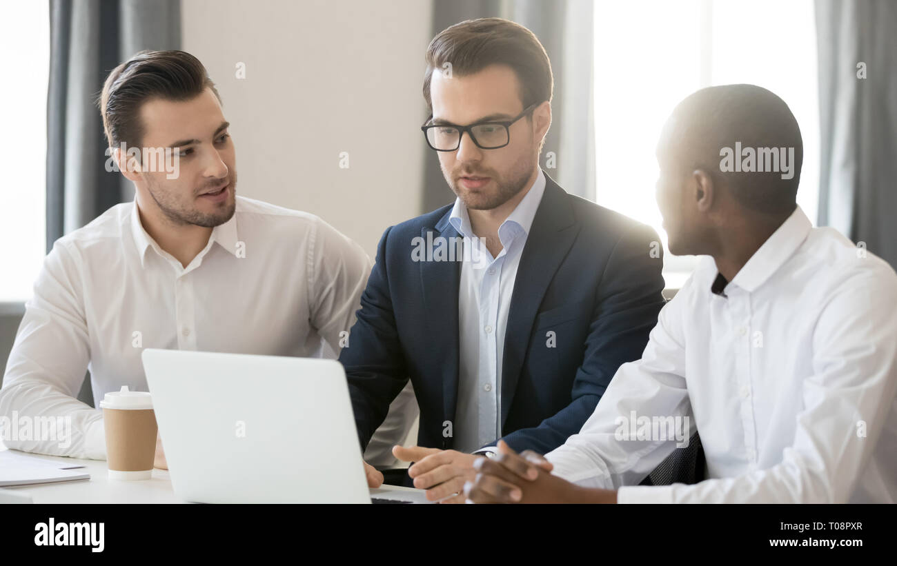 Three diverse businessmen working together collaborating on laptop in ...