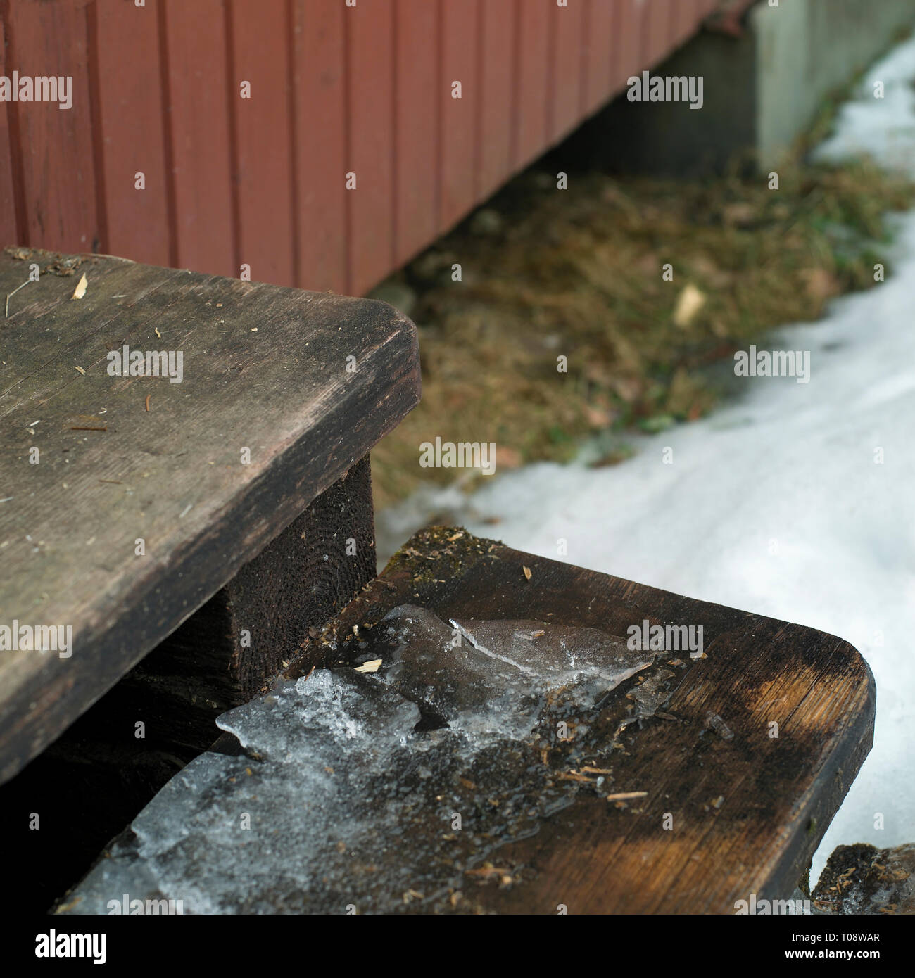 Snow melting on the wooden steps of a countryside house, outdoor square ...