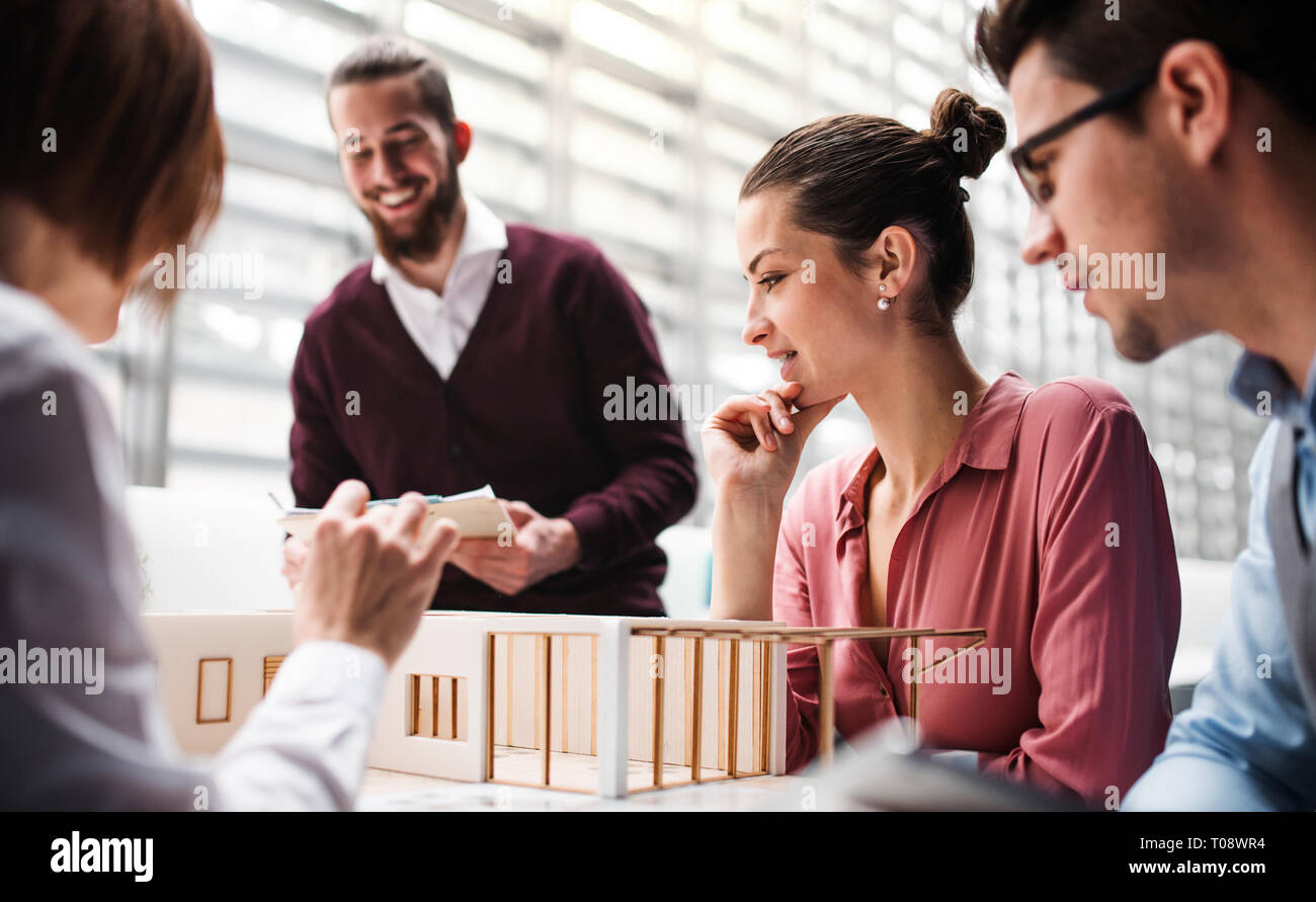 Group of young architects with model of a house standing in office ...