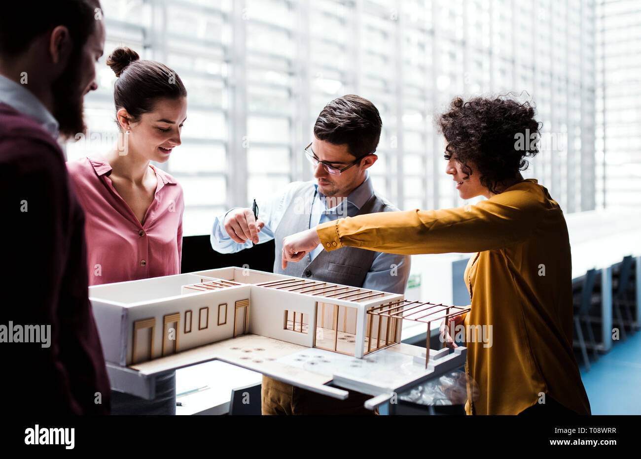 Group of young architects with model of a house standing in office ...