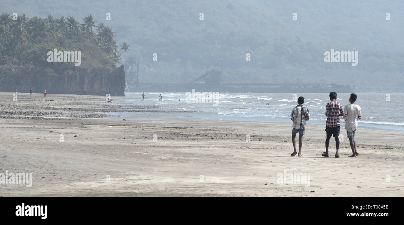 Three friends walking together along beach and fort Stock Photo - Alamy