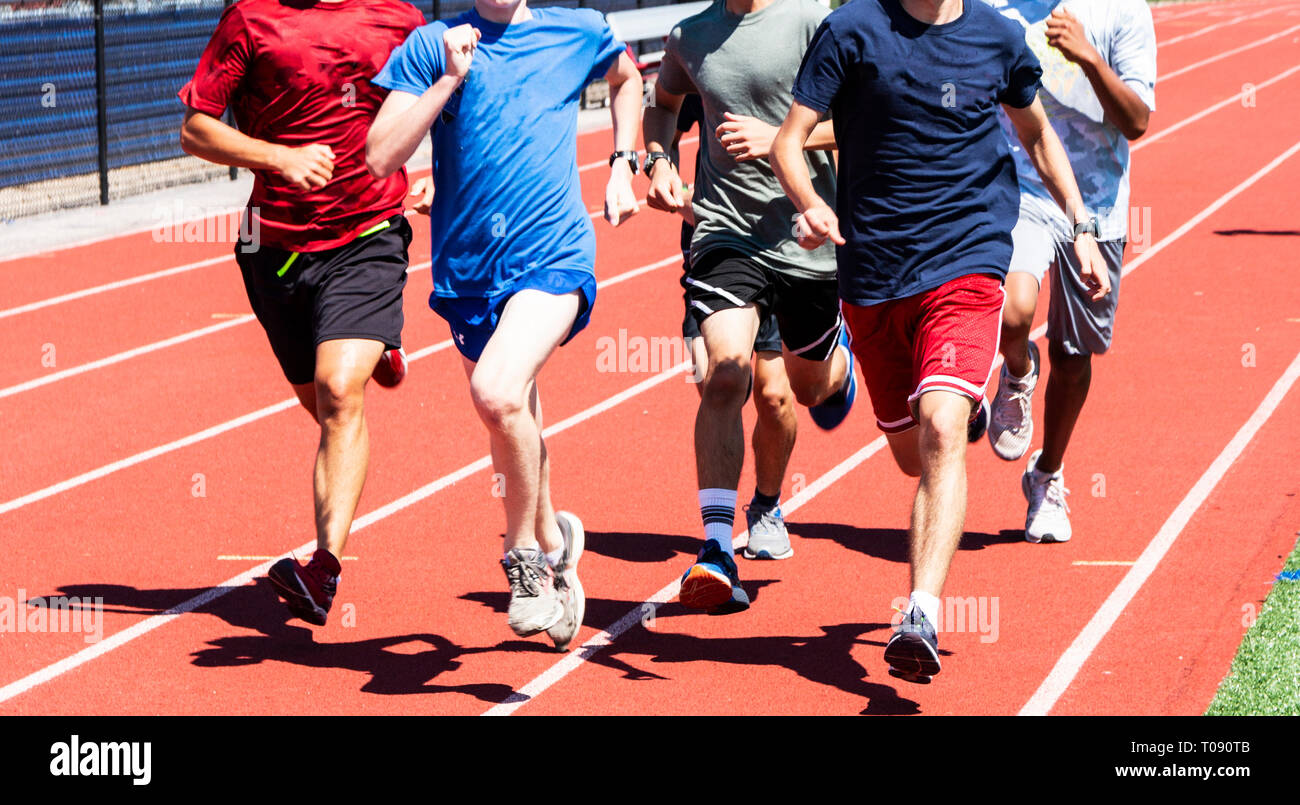 A boys high school team is running in a group fast on a track during ...