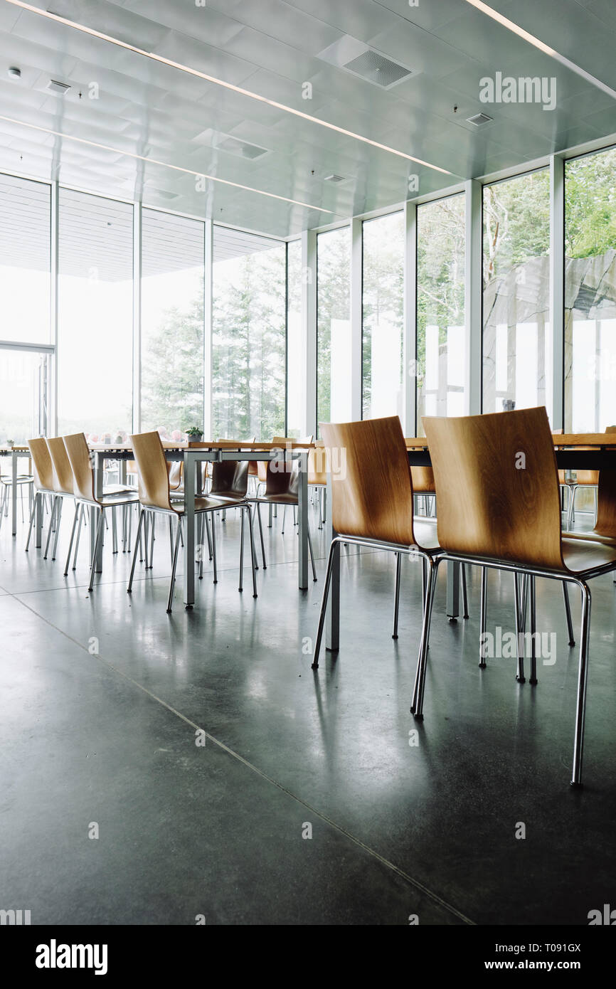 A modern glass Scandinavian cafe interior with tables and chairs in ...