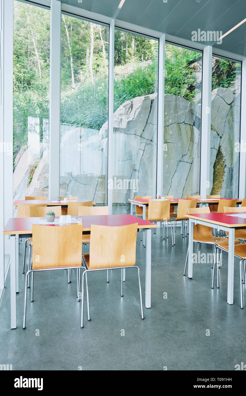 A modern glass Scandinavian cafe interior with tables and chairs in ...