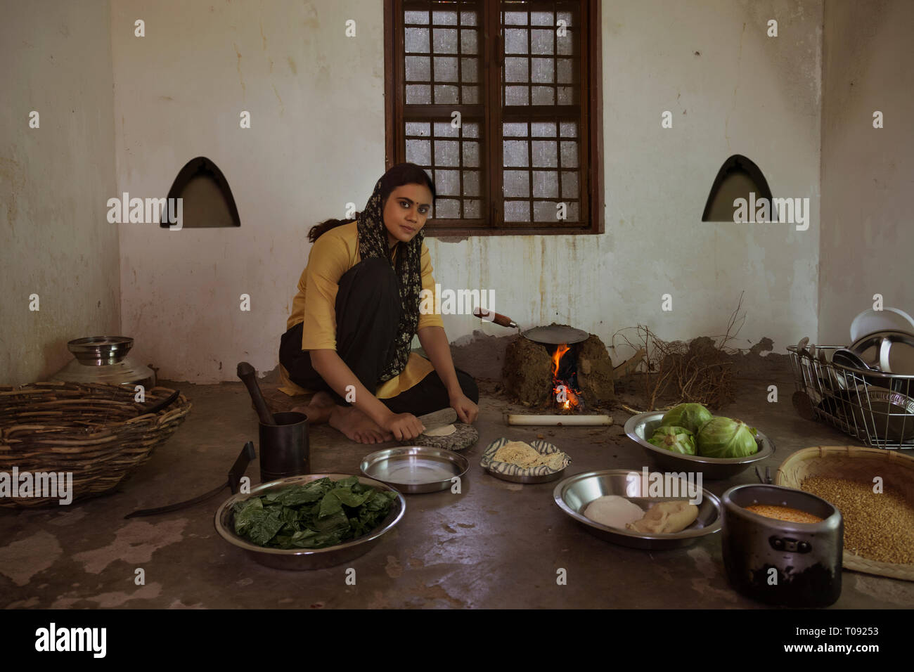 Rural woman cooking food on firewood in kitchen with utensils and ...