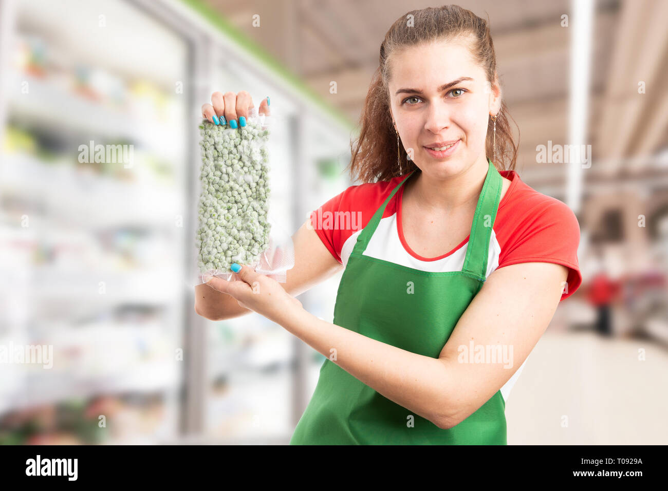 Smiling supermarket or hypermarket female worker presenting bag of ...