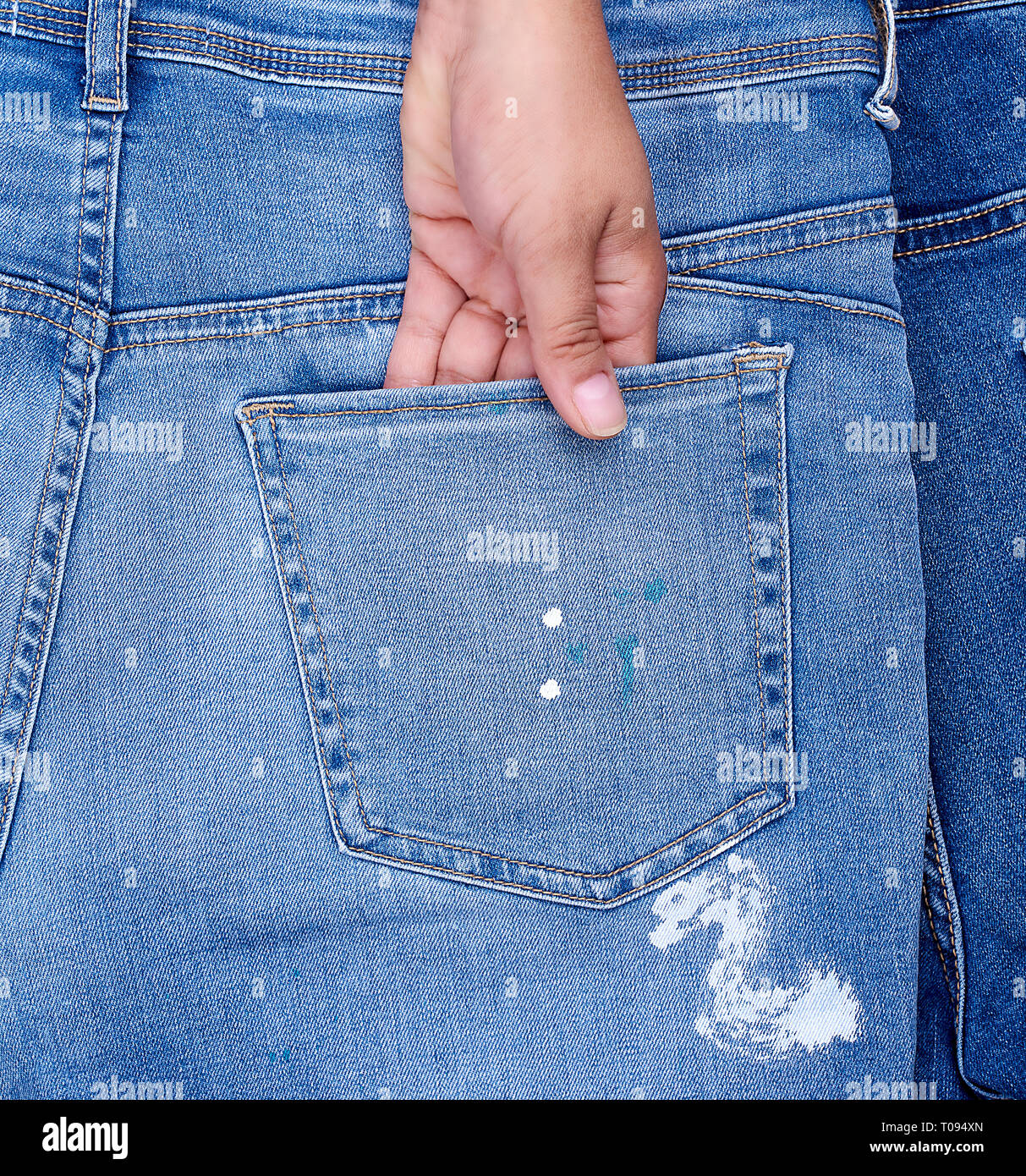 female hand is stuck in the back pocket of blue jeans, close up, full ...