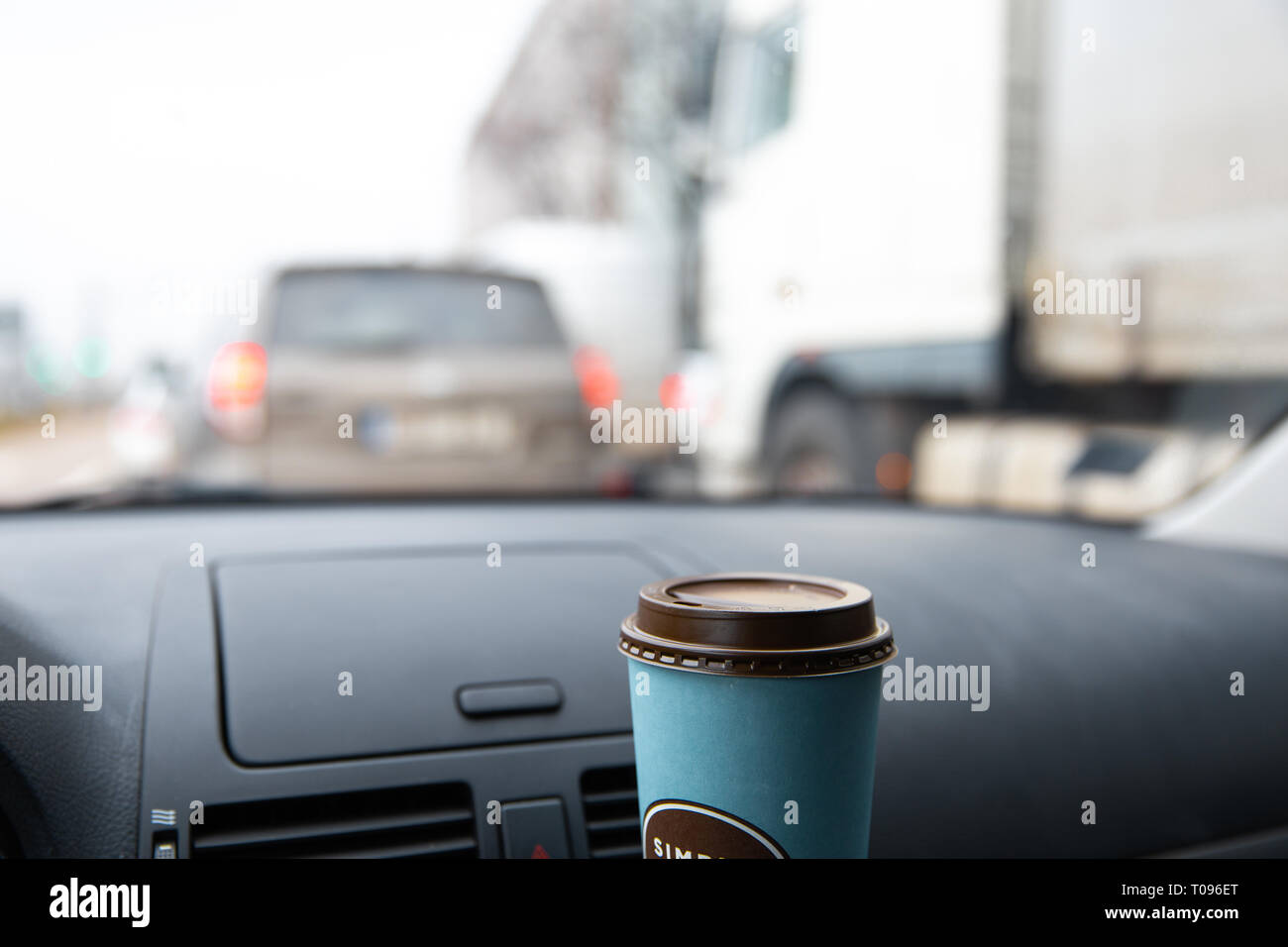 Front window view from inside a car with a blank coffee cup in the ...
