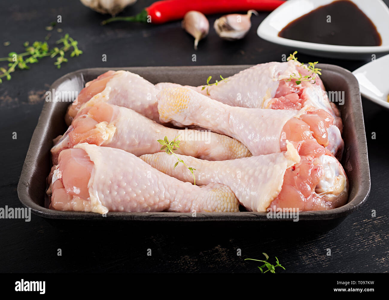 Raw uncooked chicken legs, drumsticks on dark table. Chicken meat with ...