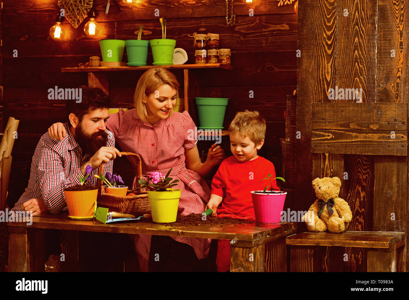 Trust concept. Little child with father and mother potting flowers ...