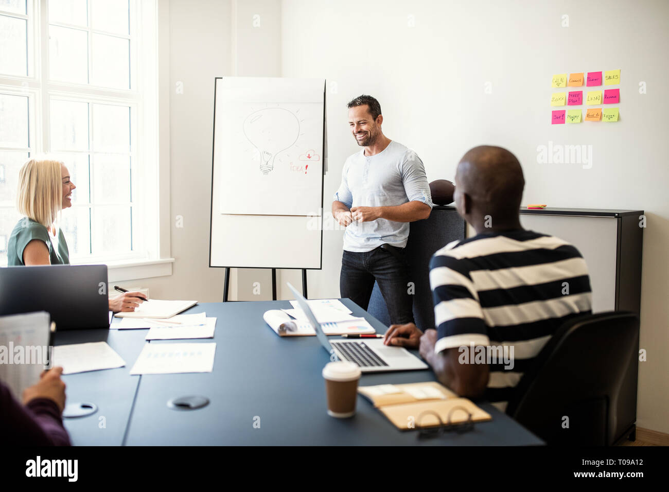 Smiling manager talking with staff sitting around a table in a ...