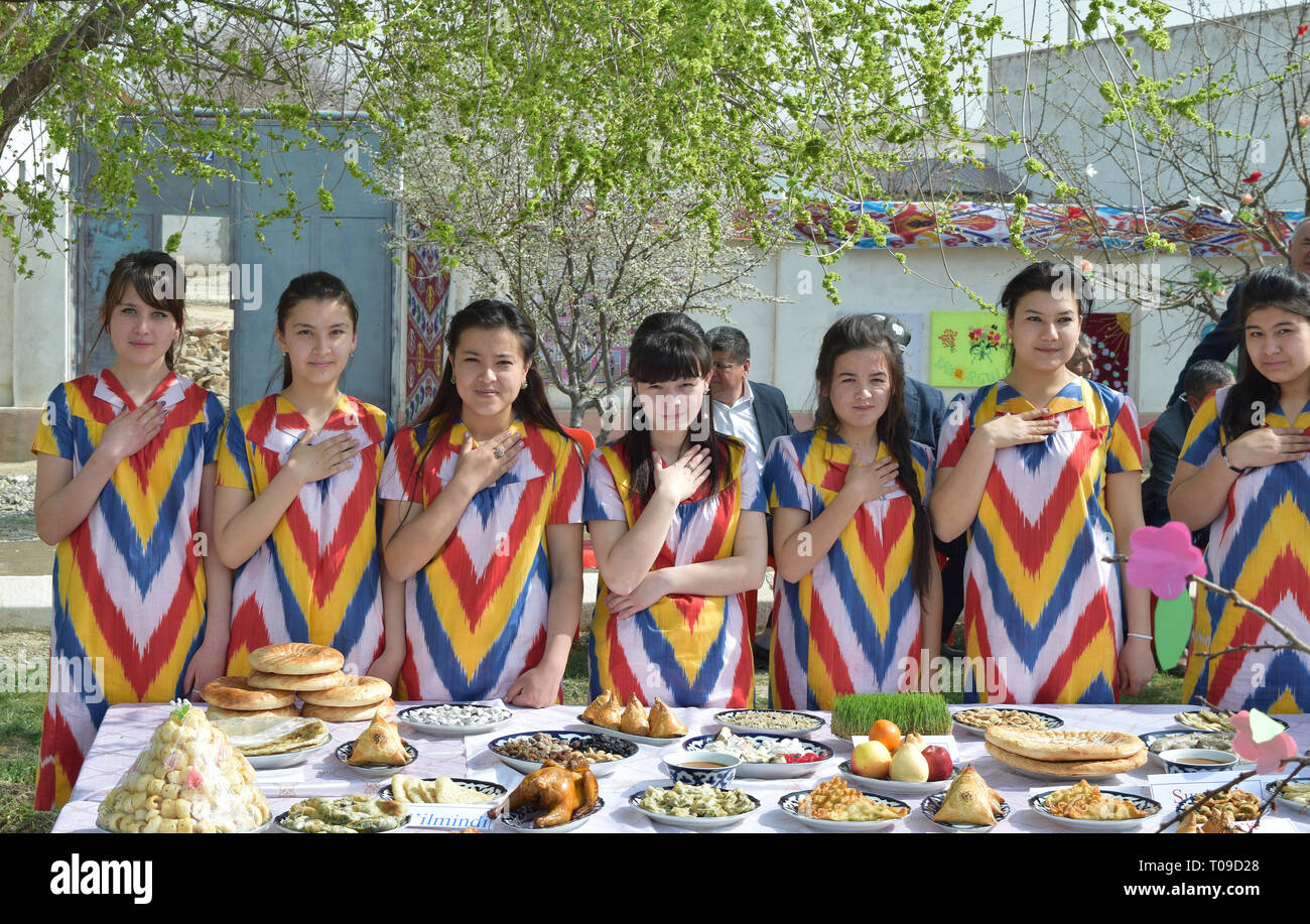 Uzbek girls in traditional dresses and a table with national dishes ...