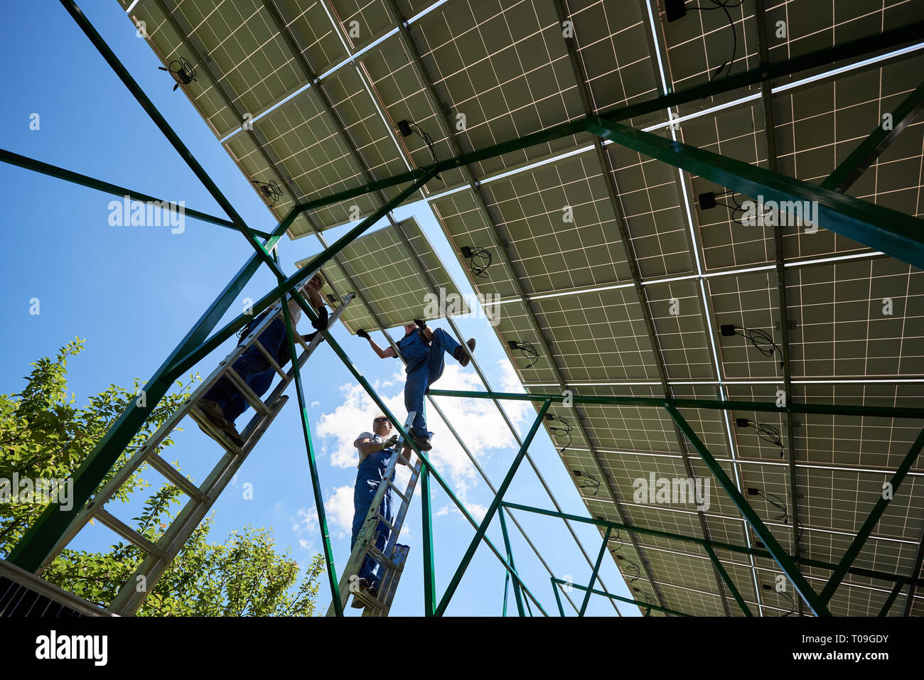 Professional workers team installing solar panels on the green metal ...