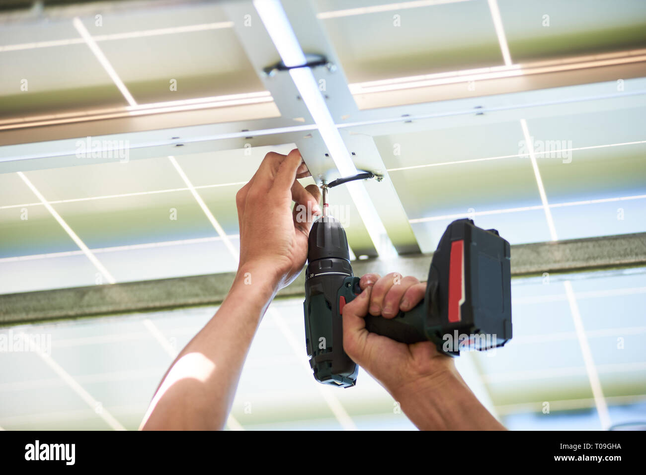 Worker using drill by solar panels installing. Innovative high-tech ...