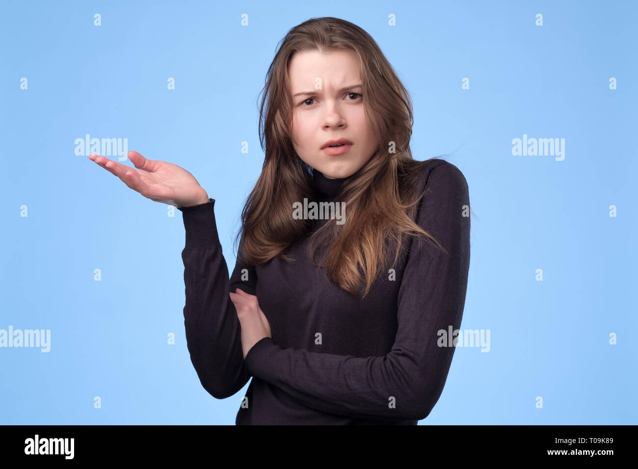 Displeased young woman frowning and staring at camera with judgemental ...