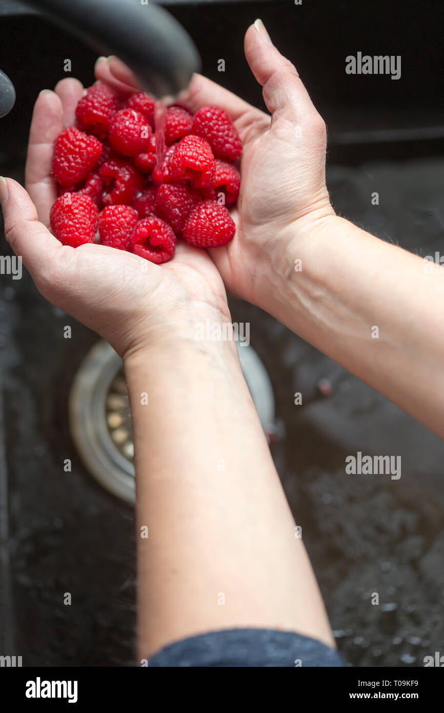 Hands washing raspberries under the water Stock Photo - Alamy