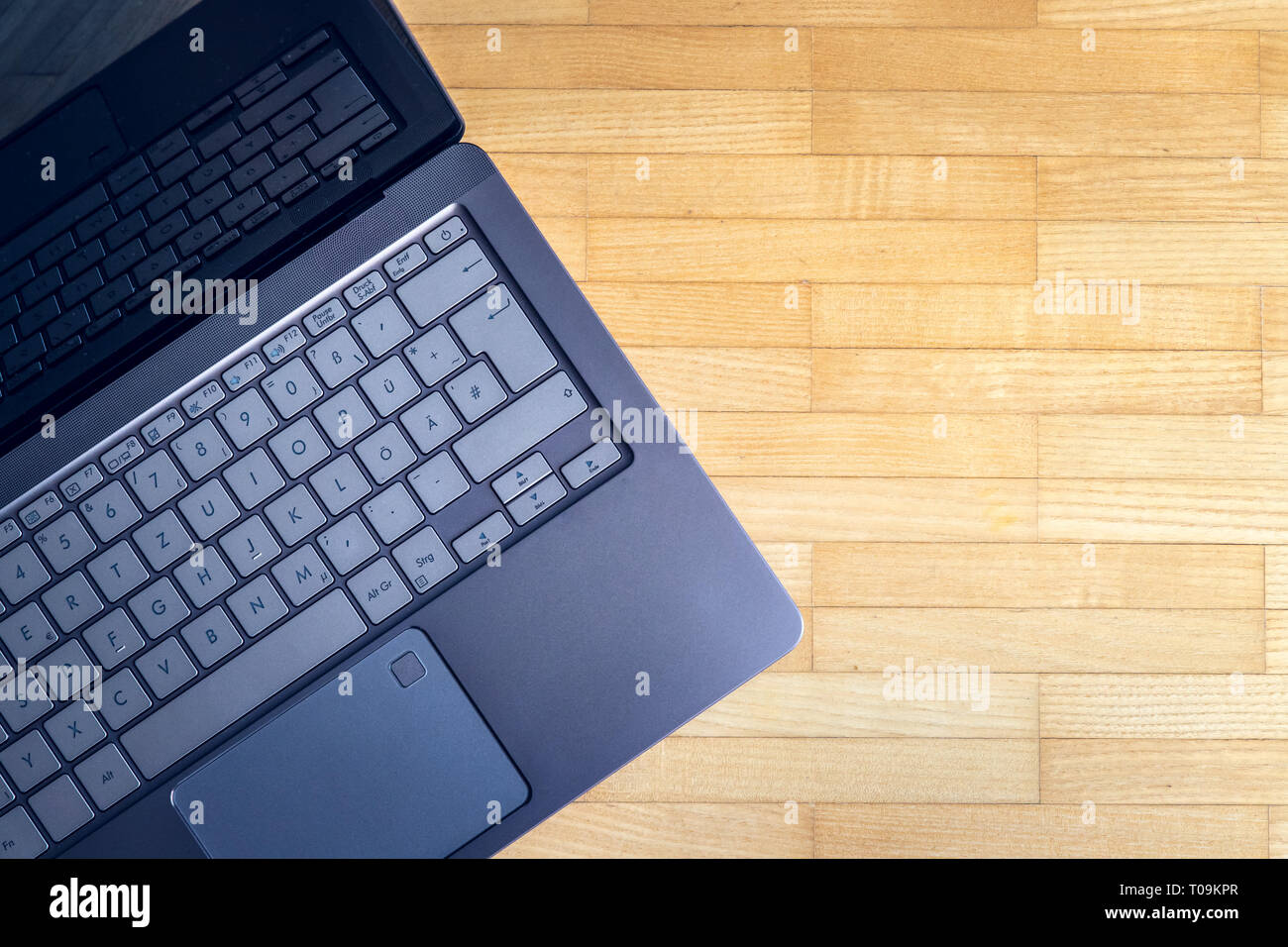 Cutout of a modern laptop keyboard on the wooden floor with text space ...
