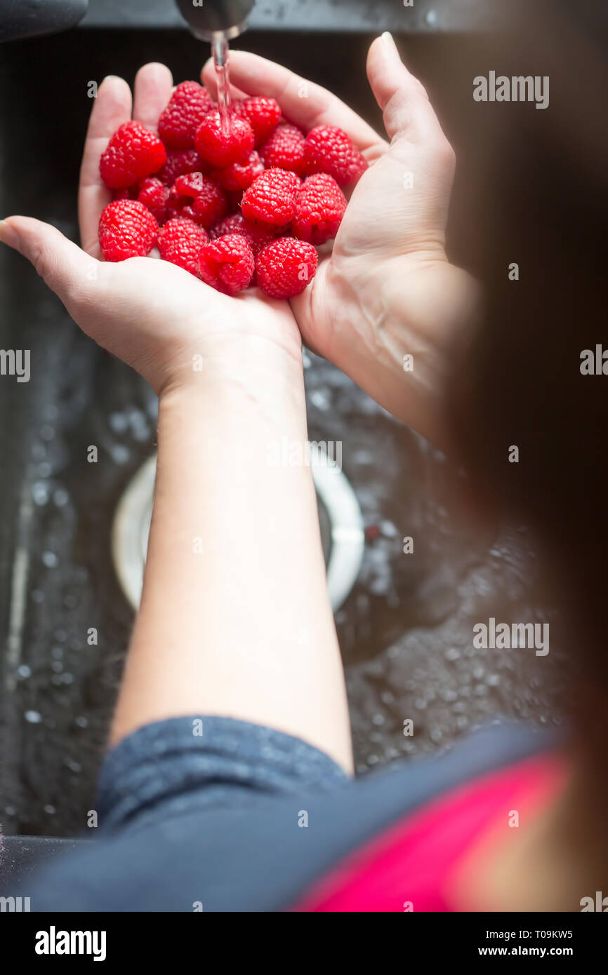 Hands washing raspberries under the water Stock Photo - Alamy
