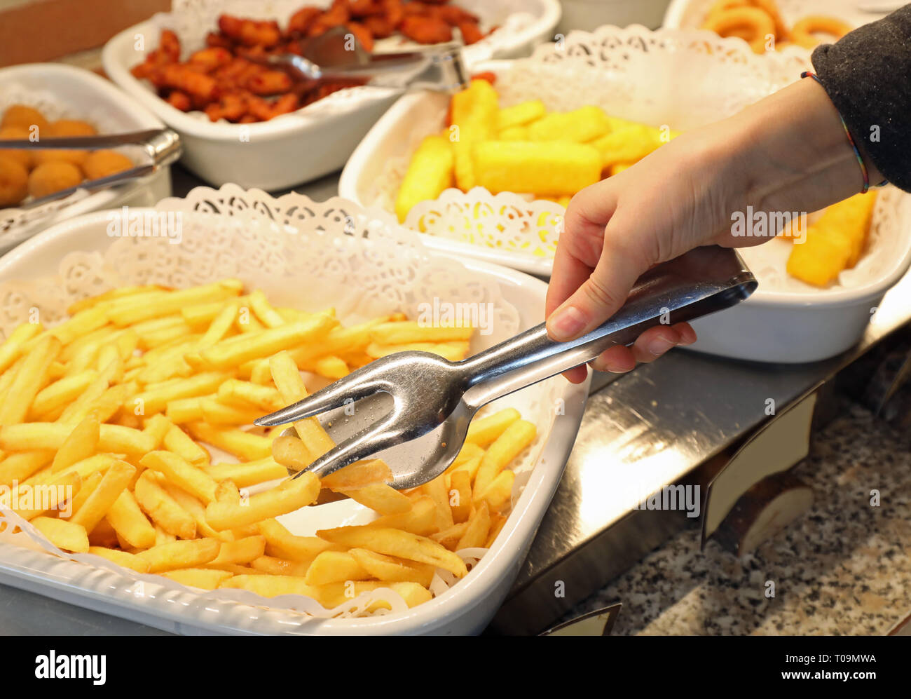 hand picking up many hot yellow french fries in the self-service ...