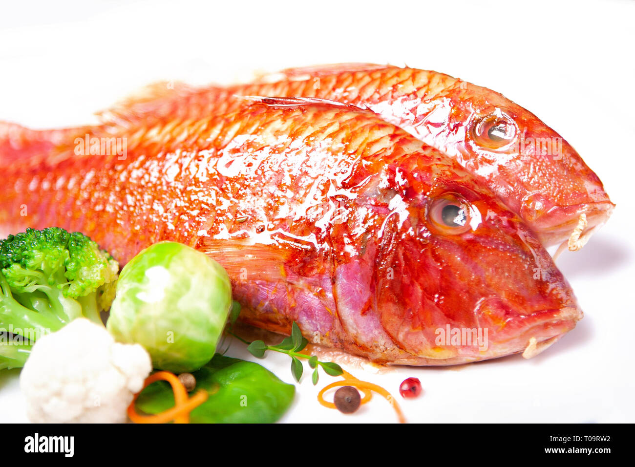 Two red mullets and vegetables on a white background Stock Photo - Alamy
