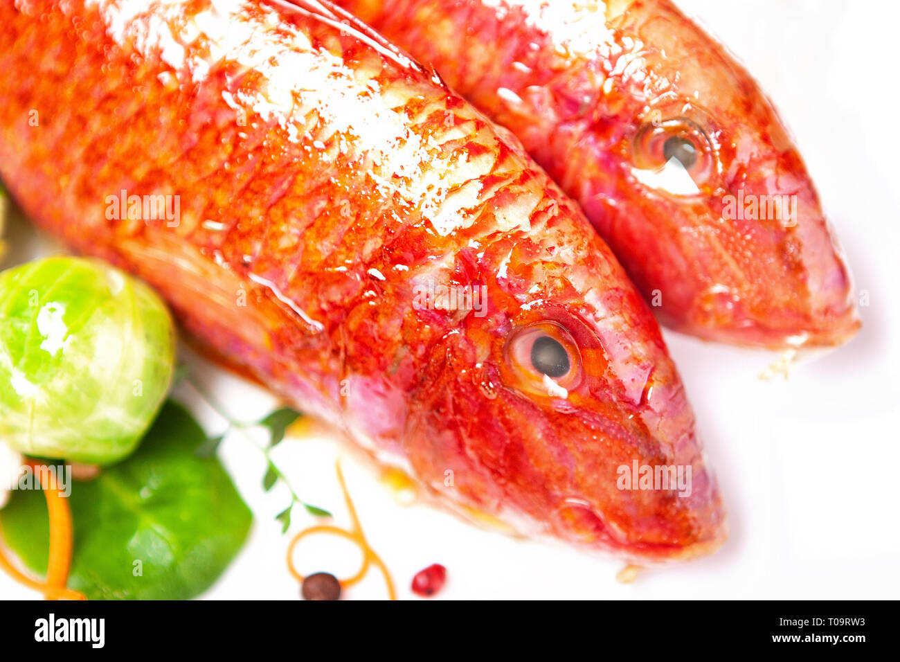 Two red mullets and vegetables on a white background Stock Photo - Alamy
